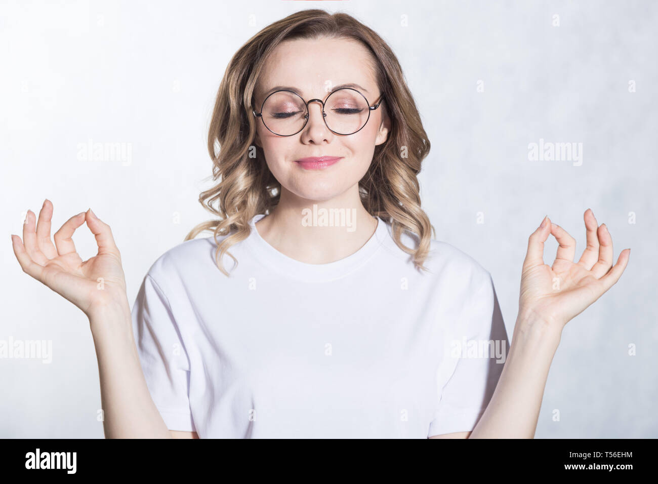 Handsome young woman in glasses shows ok sign. Body language concept ...