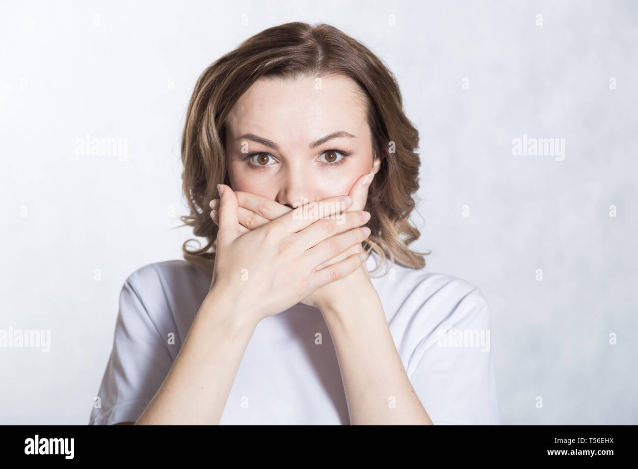 Surprised beautiful young woman covers mouth in shock Stock Photo - Alamy