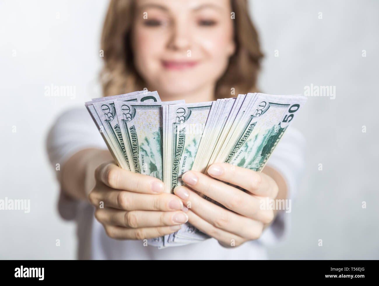 Happy young smiling woman hold us dollar money in hand over white ...