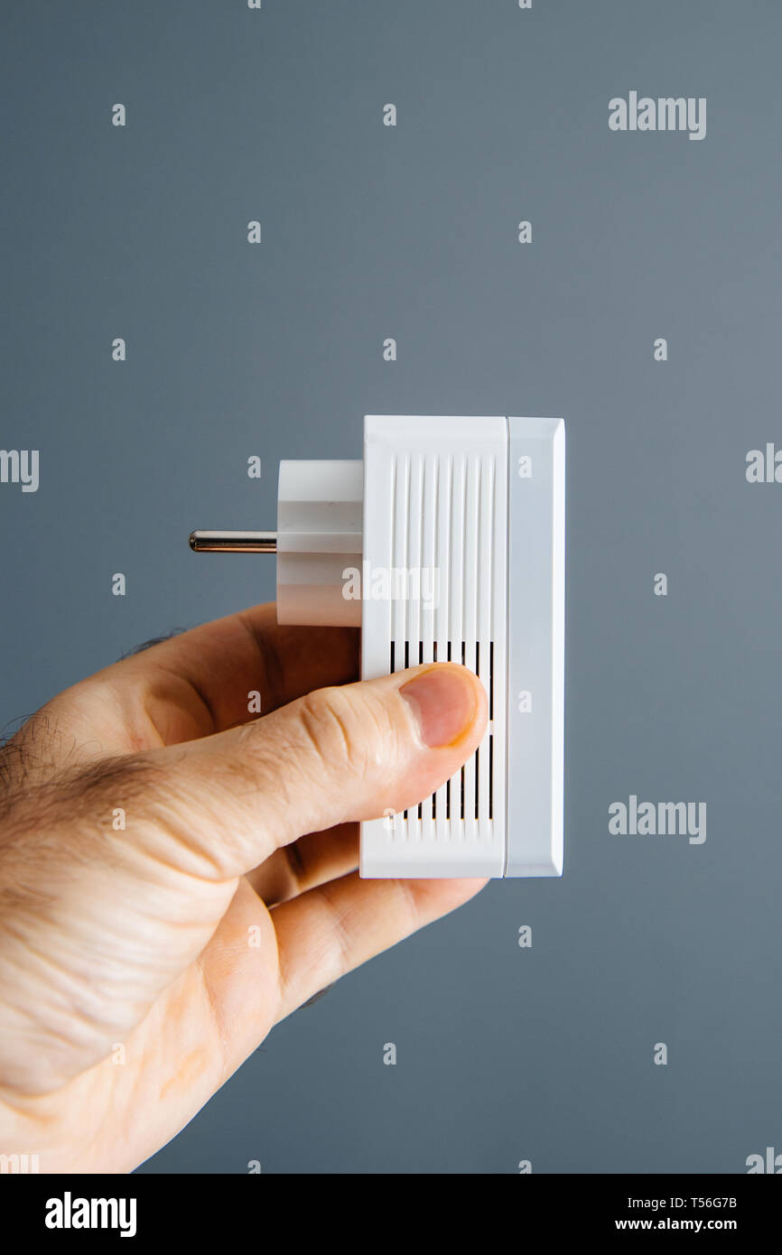 Man hand holding against light blue background a new powerline Ethernet ...