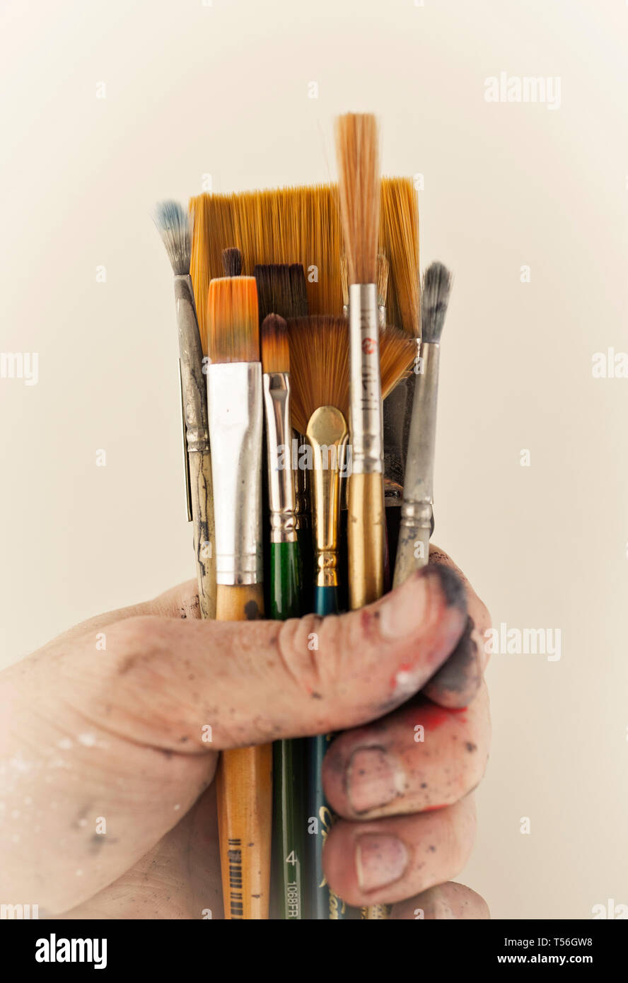 Paint brushes of various sizes in a mans hand Stock Photo - Alamy