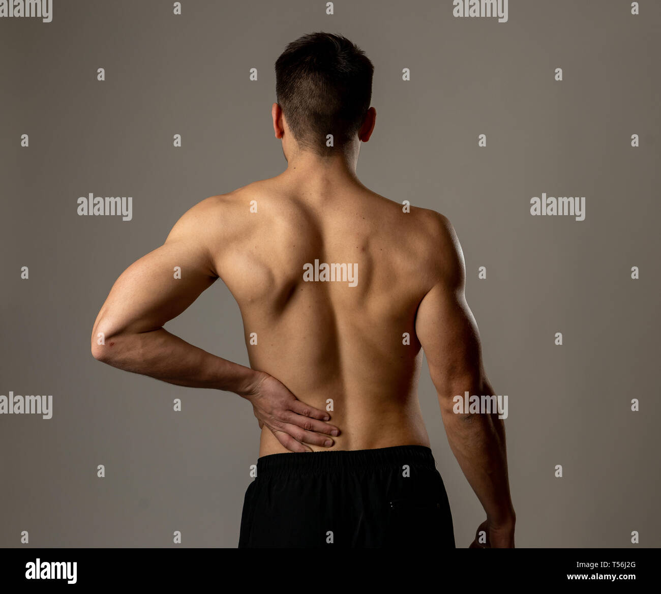 Young muscular fitness man touching and grabbing his lower back ...