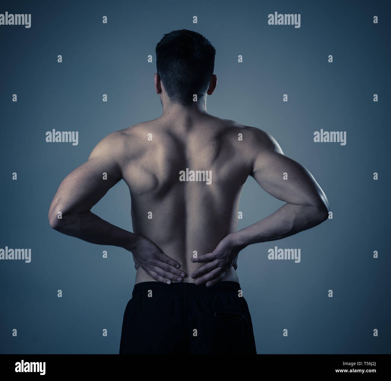 Young muscular fitness man touching and grabbing his lower back ...