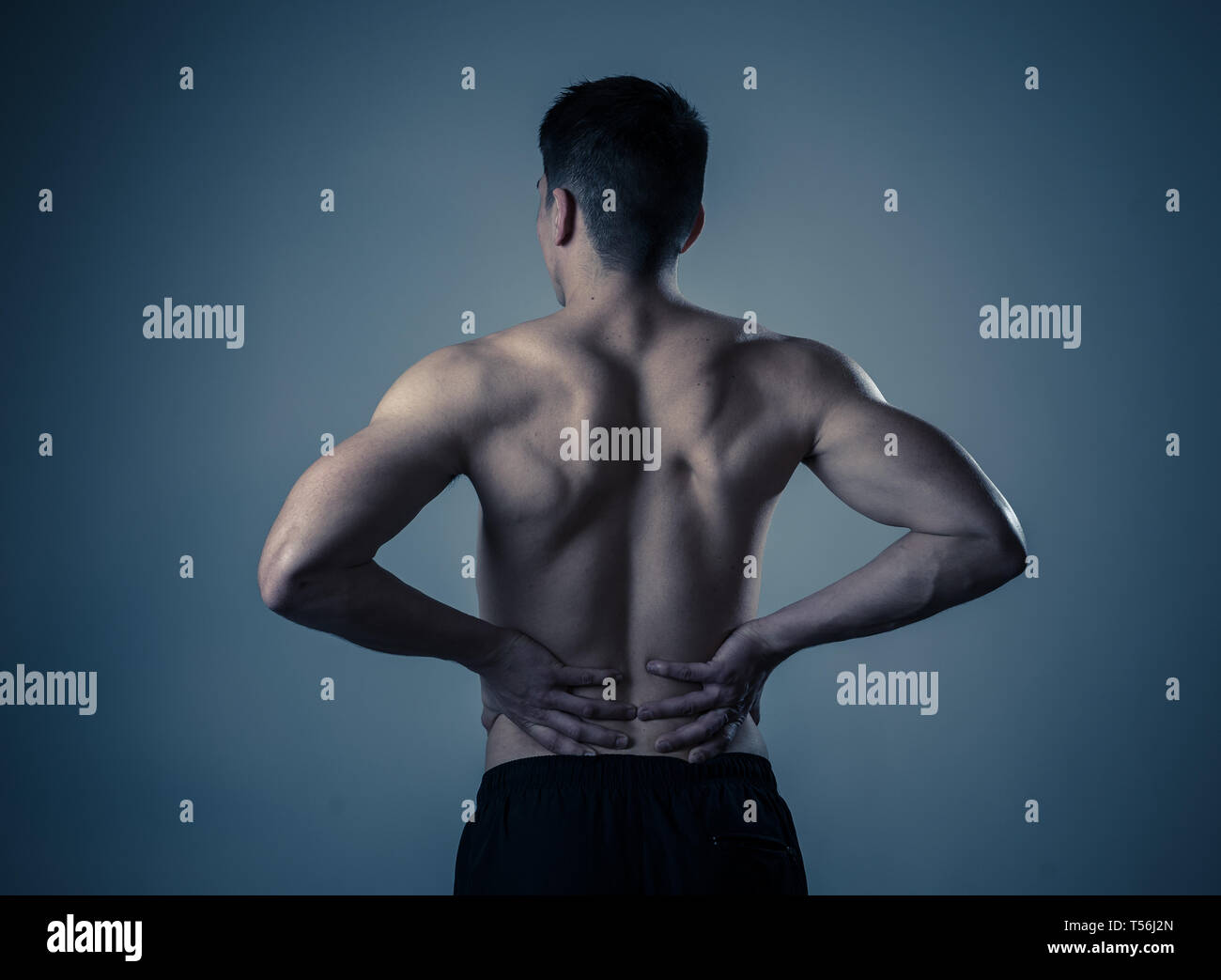 Young muscular fitness man touching and grabbing his lower back ...