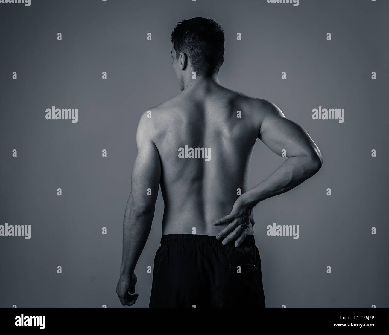 Young muscular fitness man touching and grabbing his lower back ...