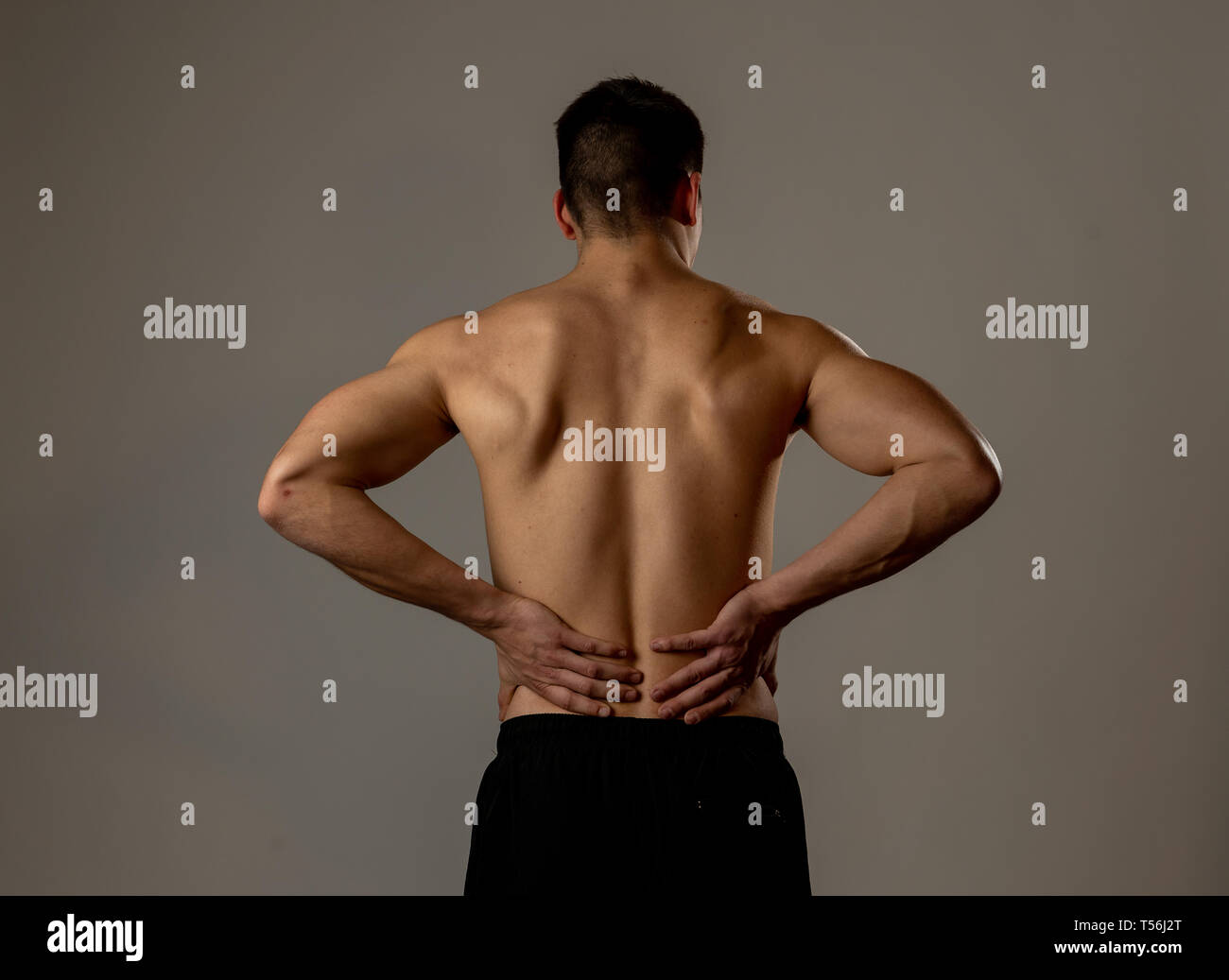 Young muscular fitness man touching and grabbing his lower back ...