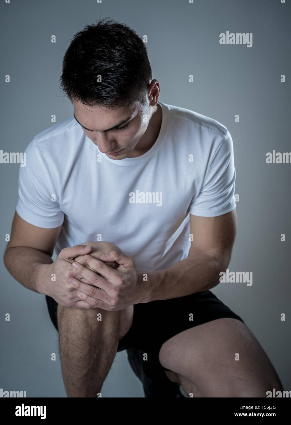 Young fit man holding knee with hands in pain after suffering muscle ...