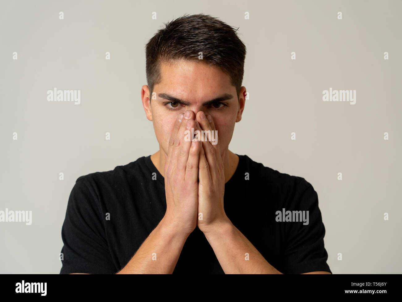 Close up of a young sad mixed race man, serious and concerned, looking ...