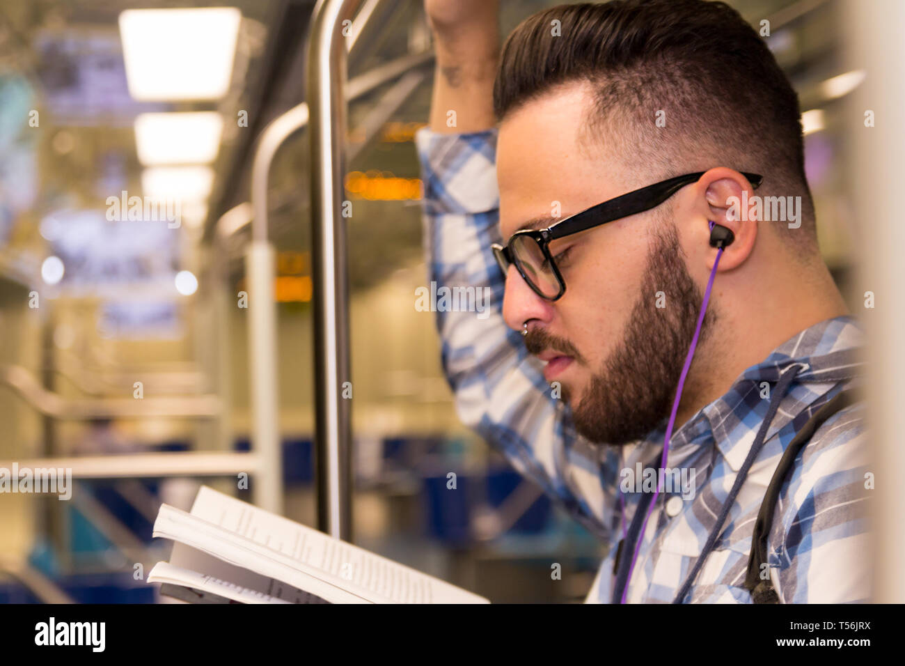 Bearded passenger college student with glasses studying while riding to ...