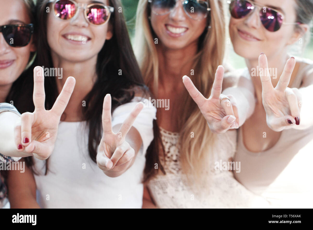 Happy smiling girlfriends showing a v hand sign Stock Photo - Alamy
