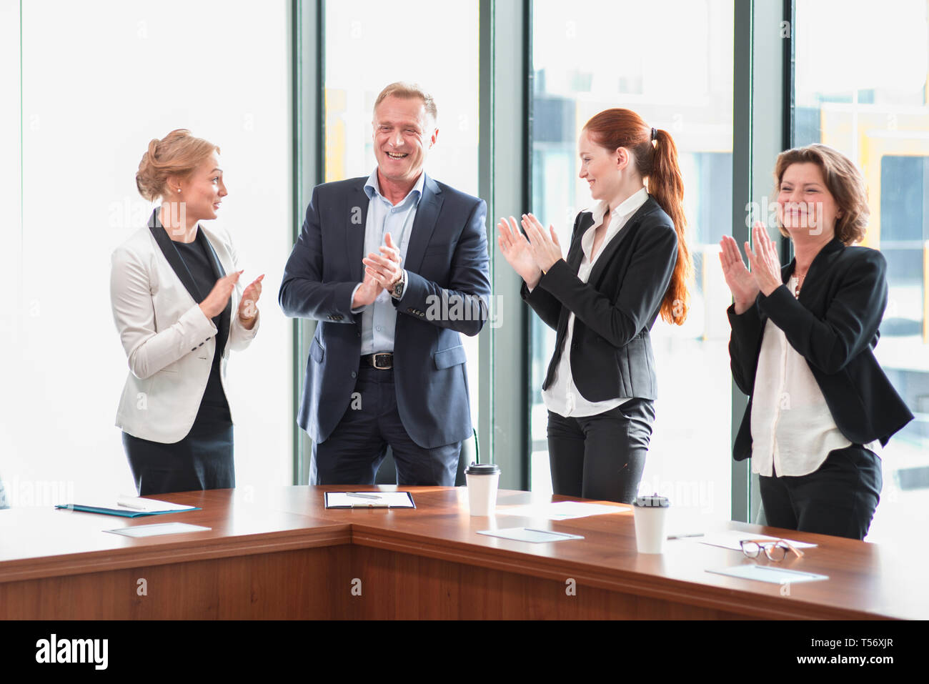 Business people group clapping and smiling in office standing around ...
