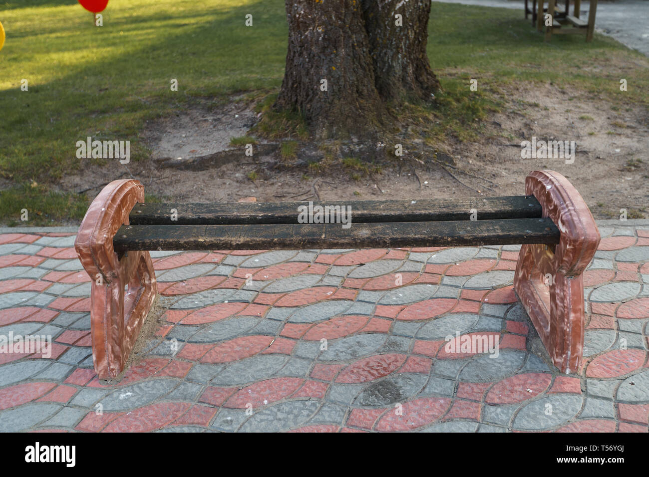 Small city bench standing on a pavement near a tree Stock Photo - Alamy