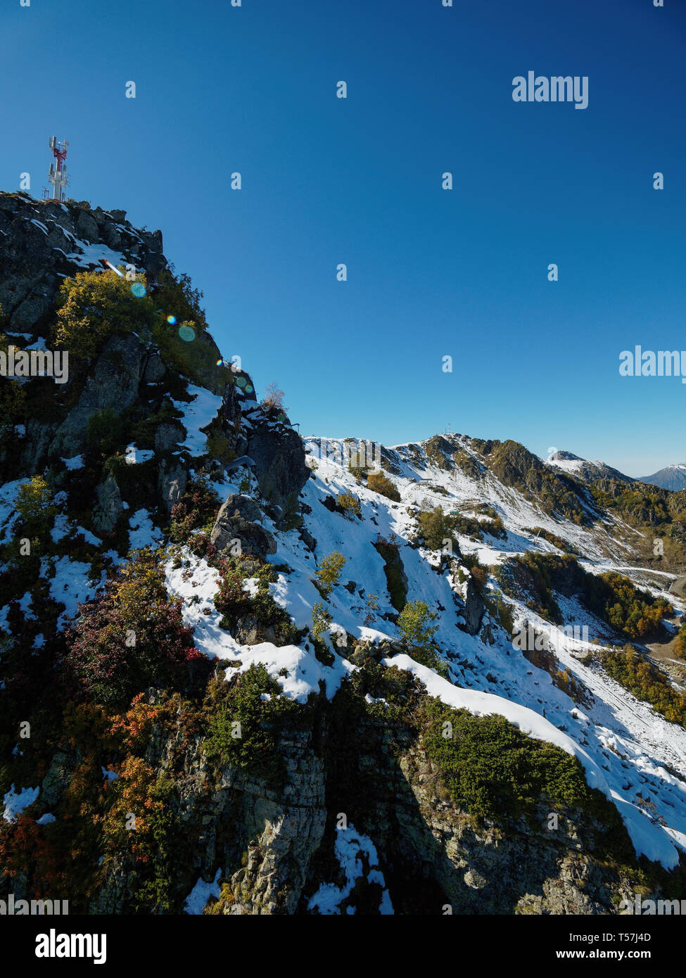 Snowy mountain peak with green and yellow trees. Clear blue sky Stock ...