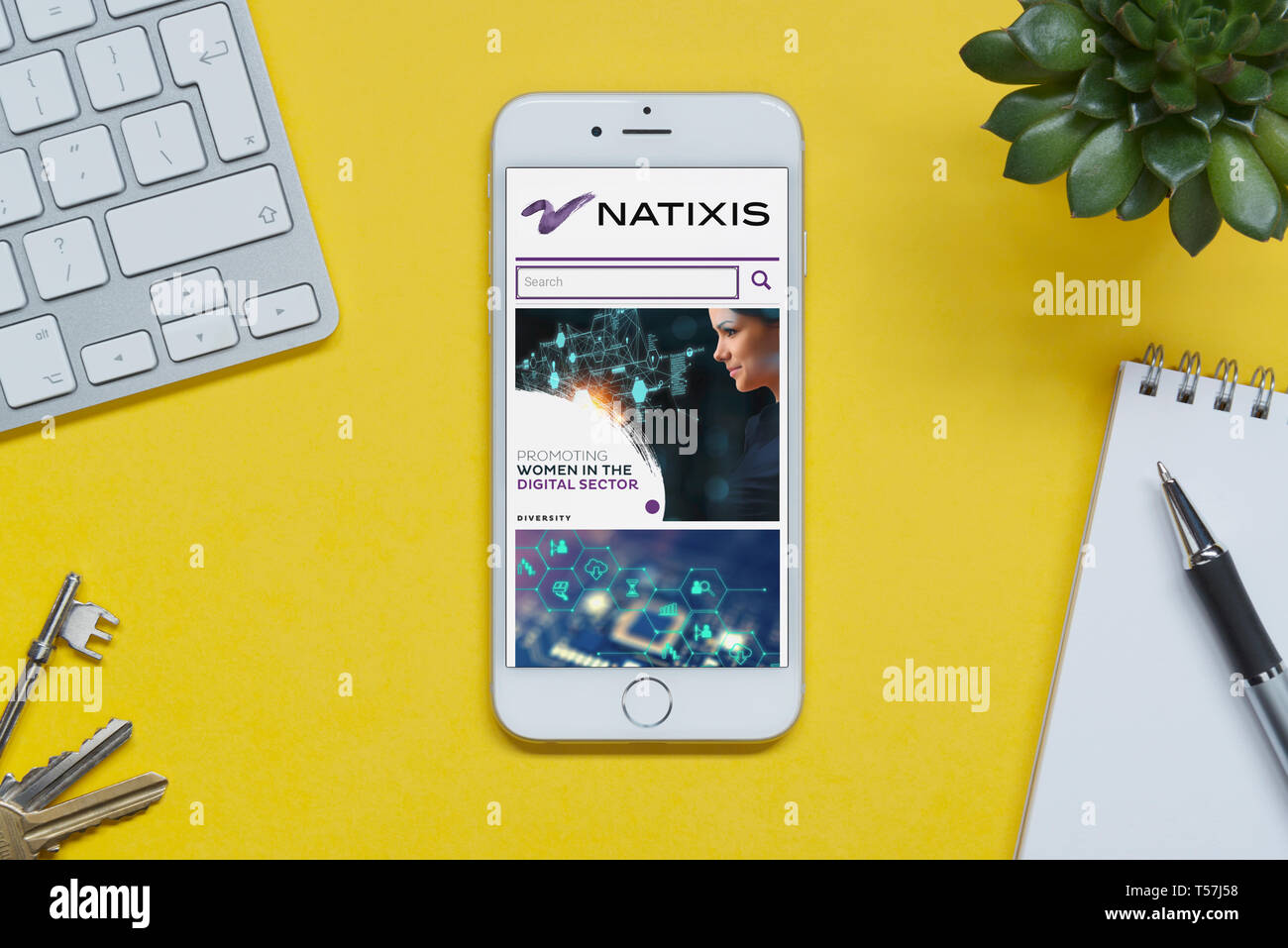 An iPhone showing the Natixis website rests on a yellow background ...