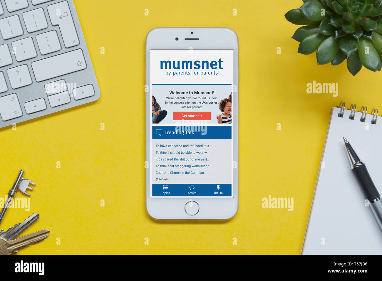 An iPhone showing the Mumsnet website rests on a yellow background ...
