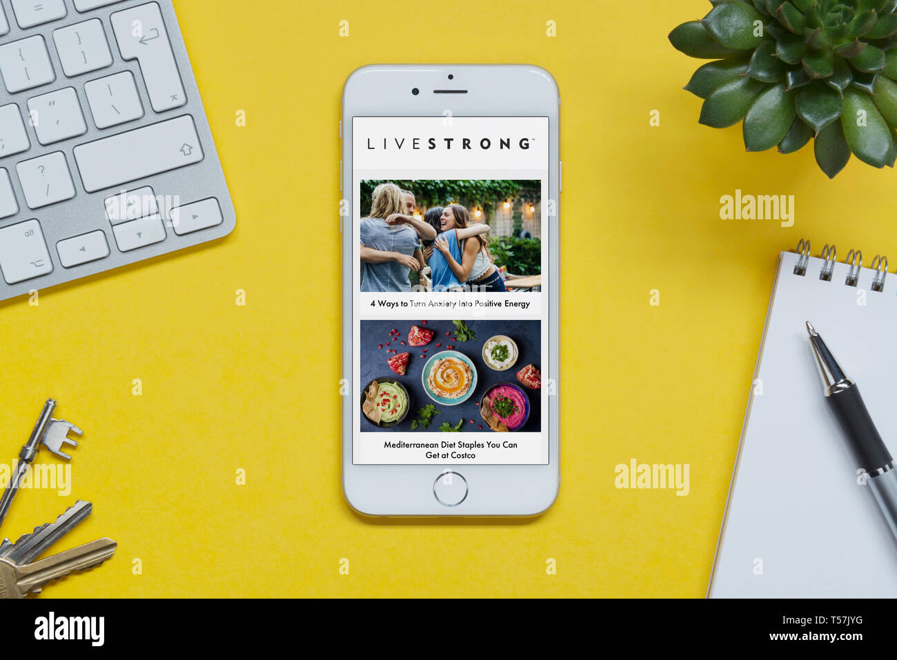 An iPhone showing the Livestrong website rests on a yellow background ...