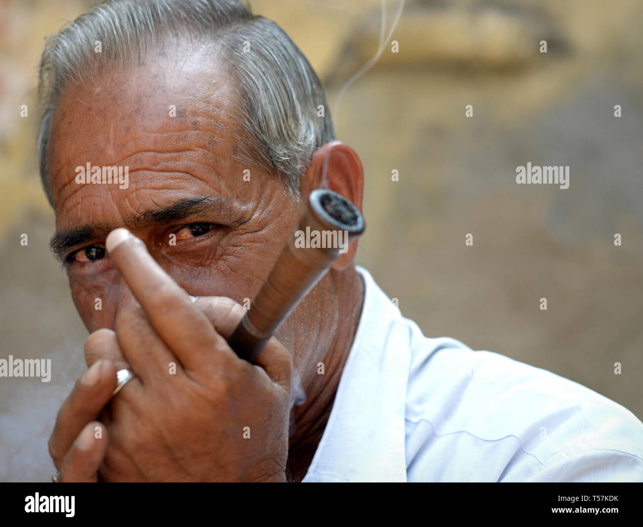 Middle-aged Indian Rajasthani man smokes tobacco in his chillum pipe in ...