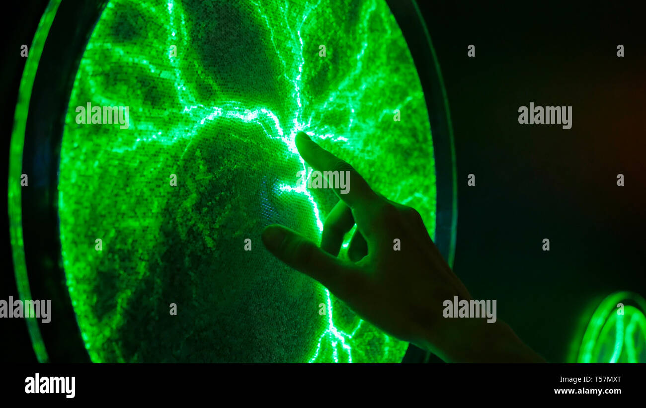 Interactive exposition in science museum. Woman touching plasma panel ...