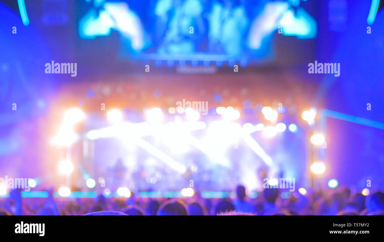 Abstract defocused concert lighting bokeh on stage. People silhouette ...