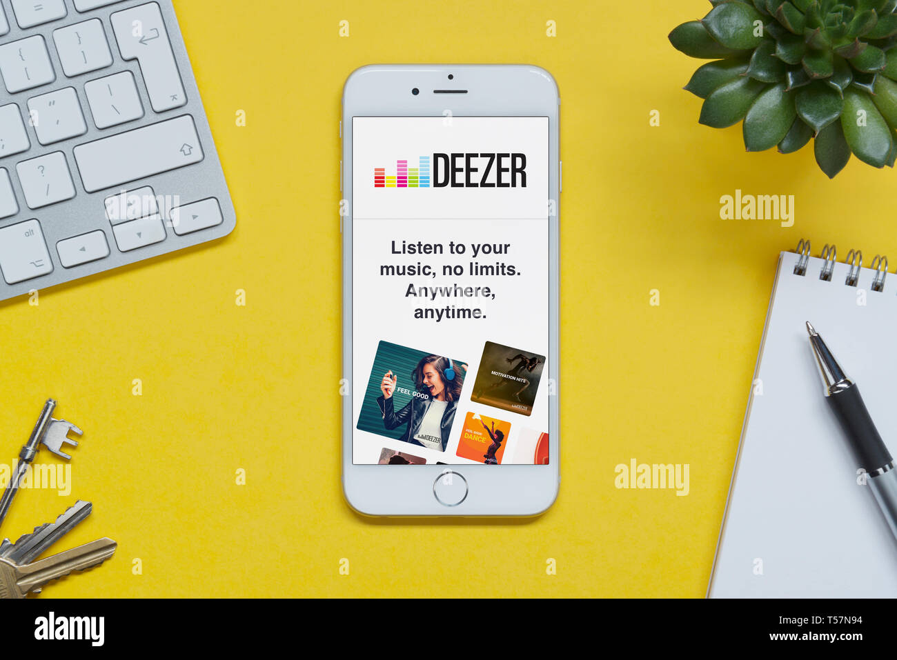 An iPhone showing the Deezer website rests on a yellow background table ...