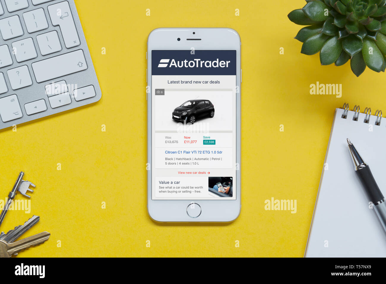 An iPhone showing the AutoTrader website rests on a yellow background ...