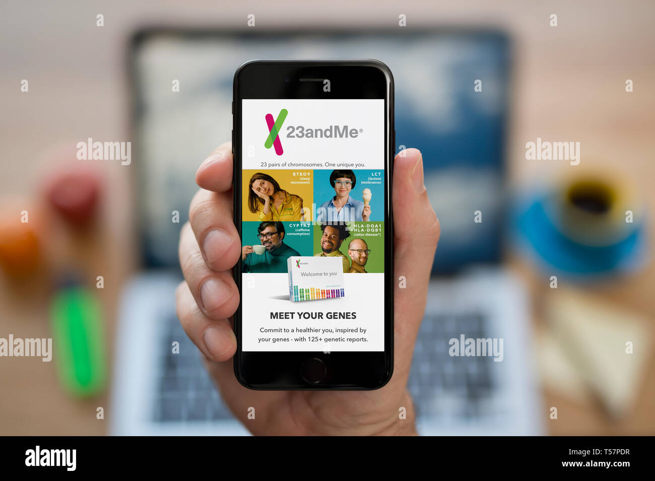 A man looks at his iPhone which displays the 23andMe logo (Editorial ...