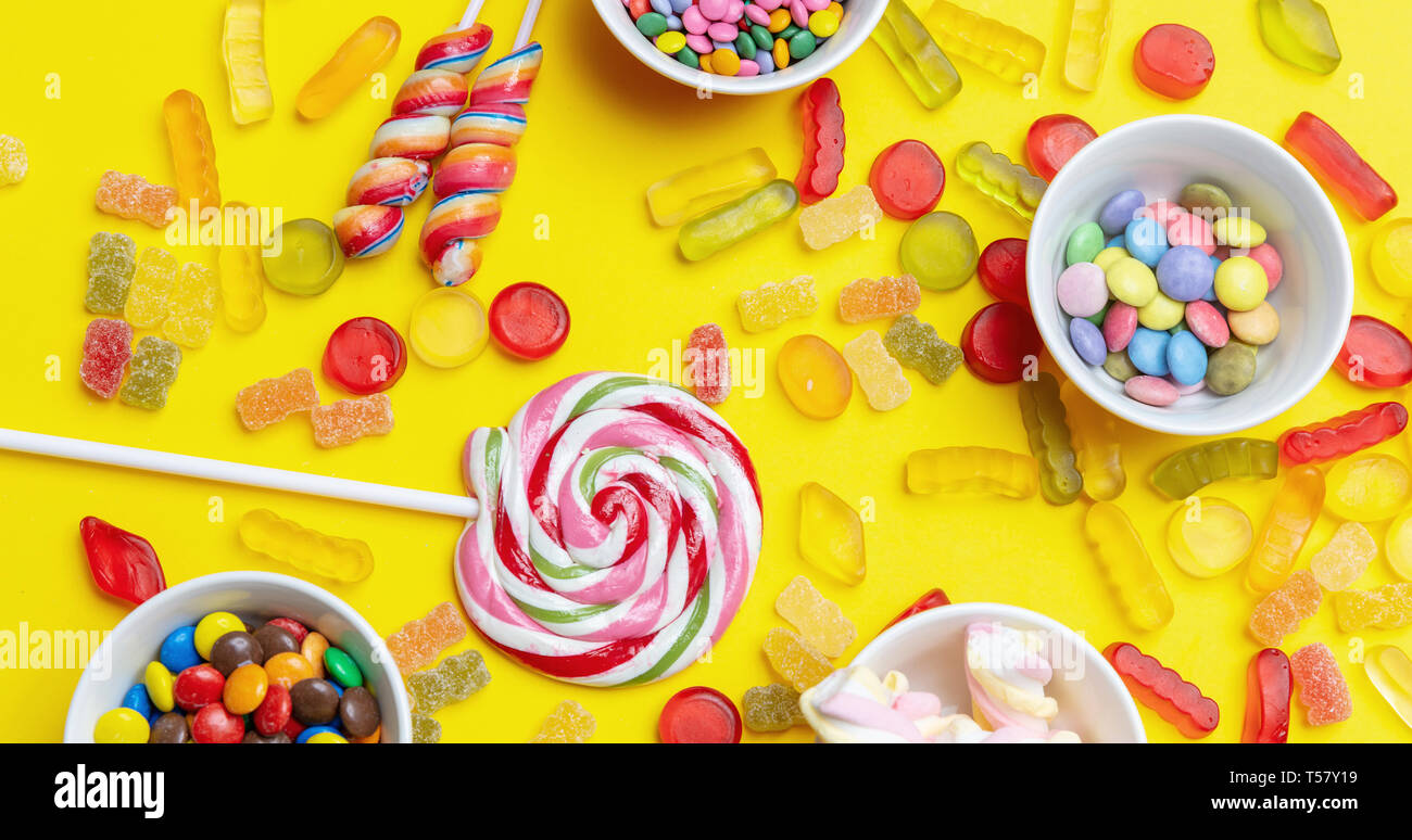 Candies assortment on yellow color background, top view. Kids birthday ...