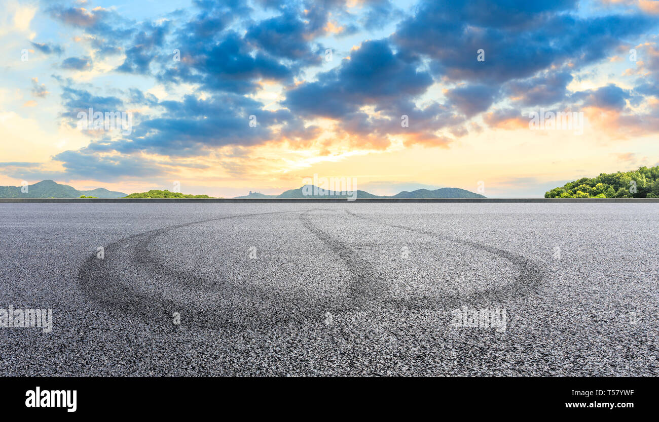 Asphalt race track ground and mountains with beautiful clouds at sunset ...