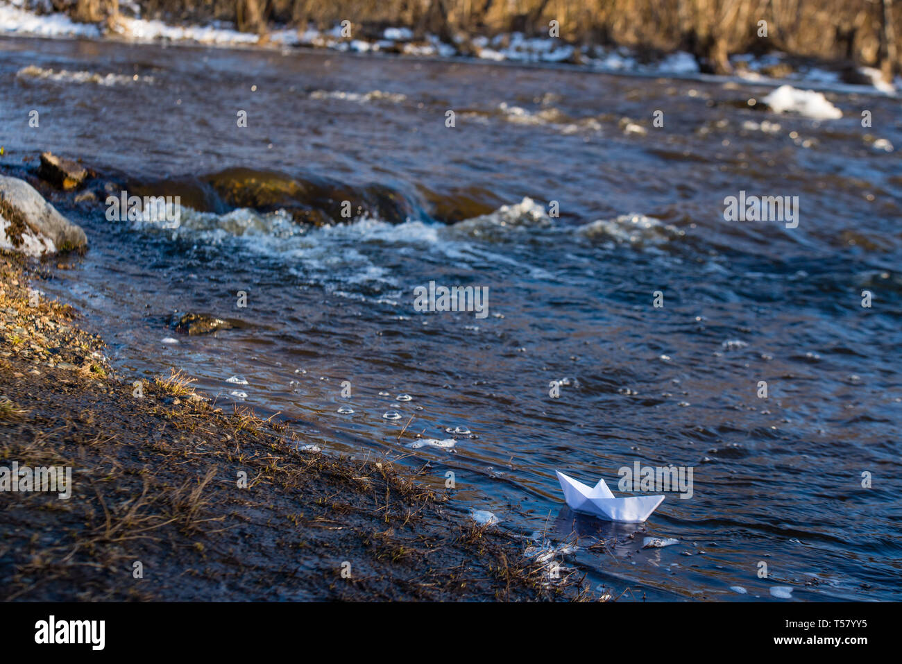 A paper boat on a turbulent stream of water struggles with the flow ...