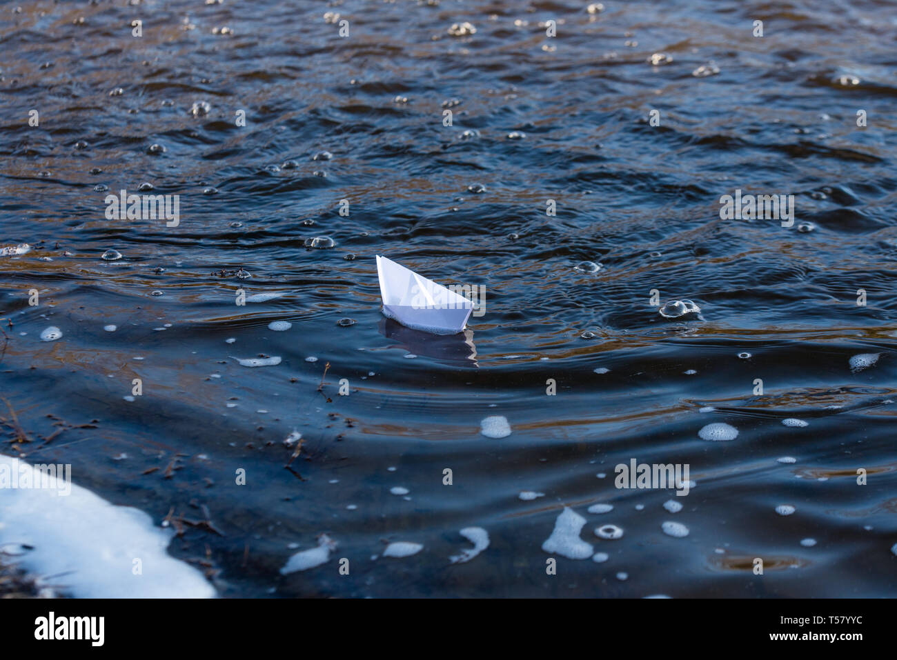 A paper boat on a turbulent stream of water struggles with the flow ...