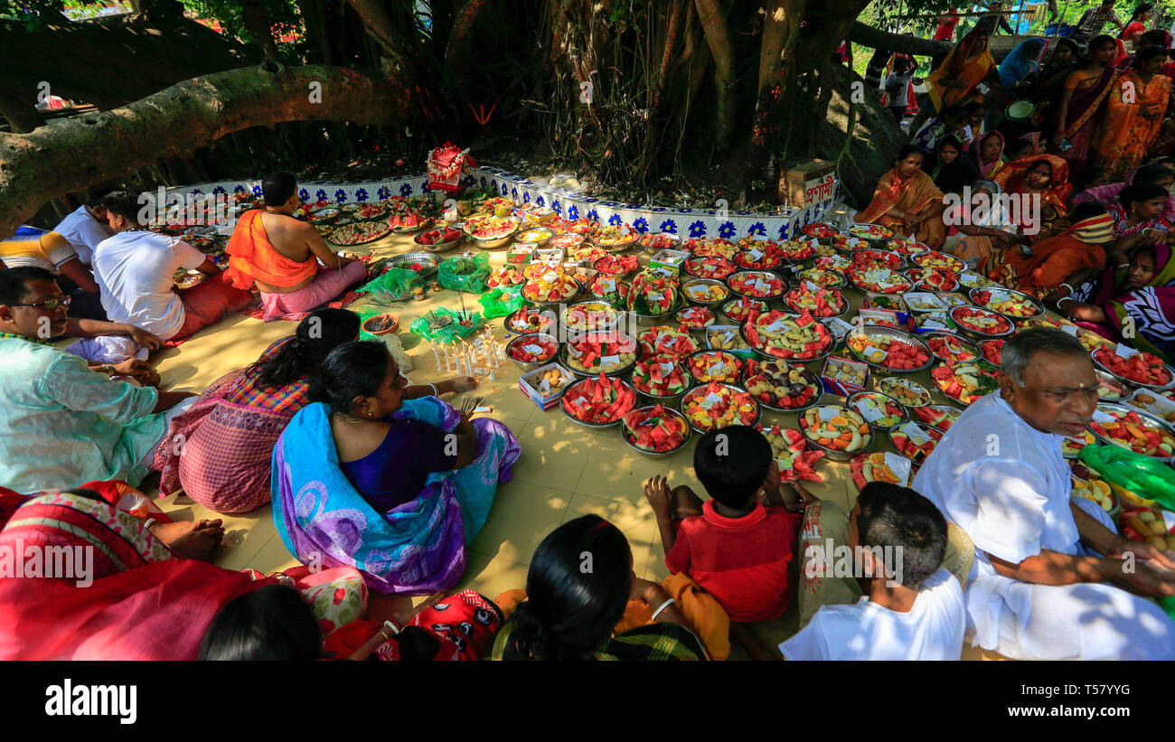 Devotees sit beside arrays of offerings placed under the ancient banyan ...