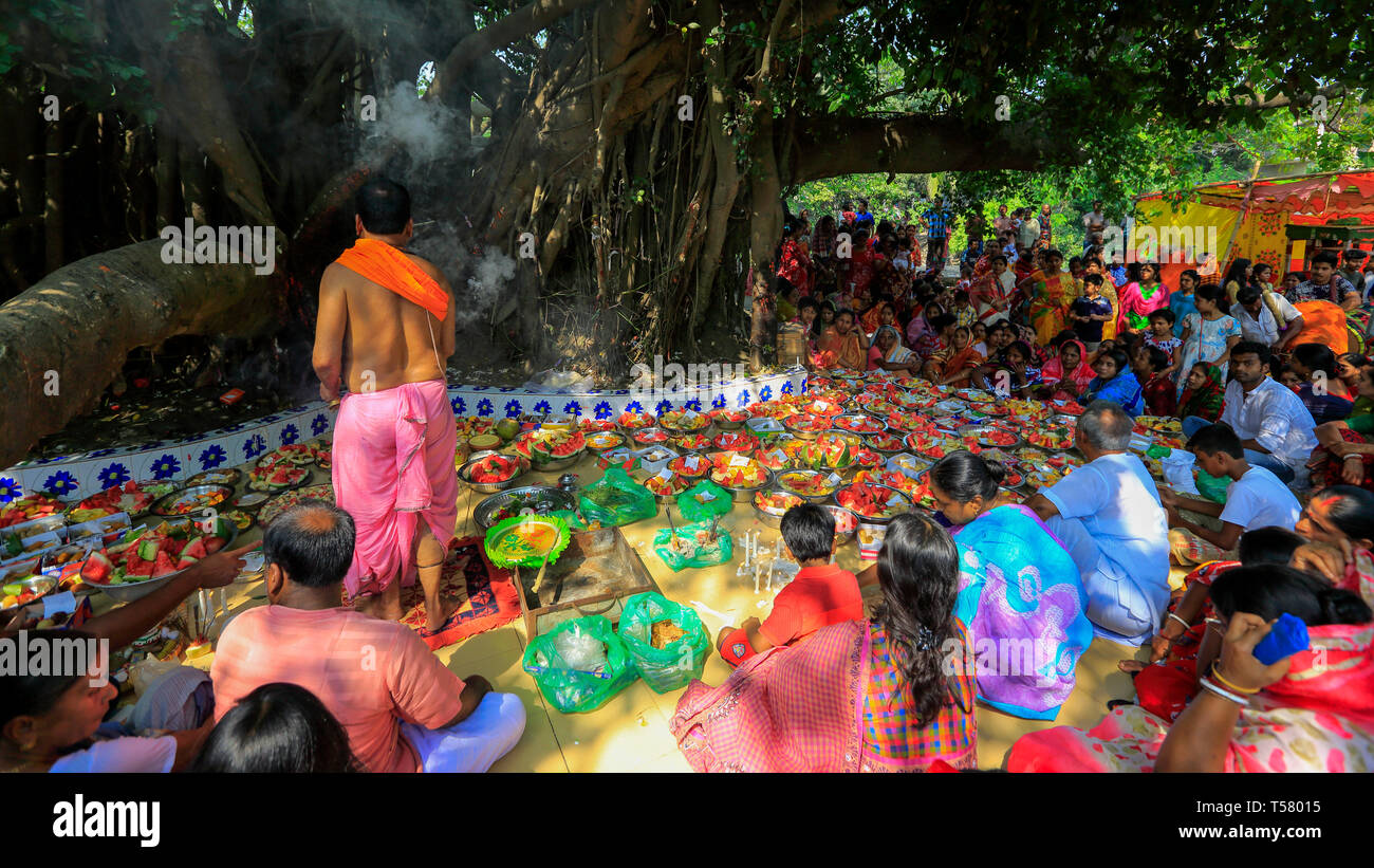 Devotees sit beside arrays of offerings placed under the ancient banyan ...