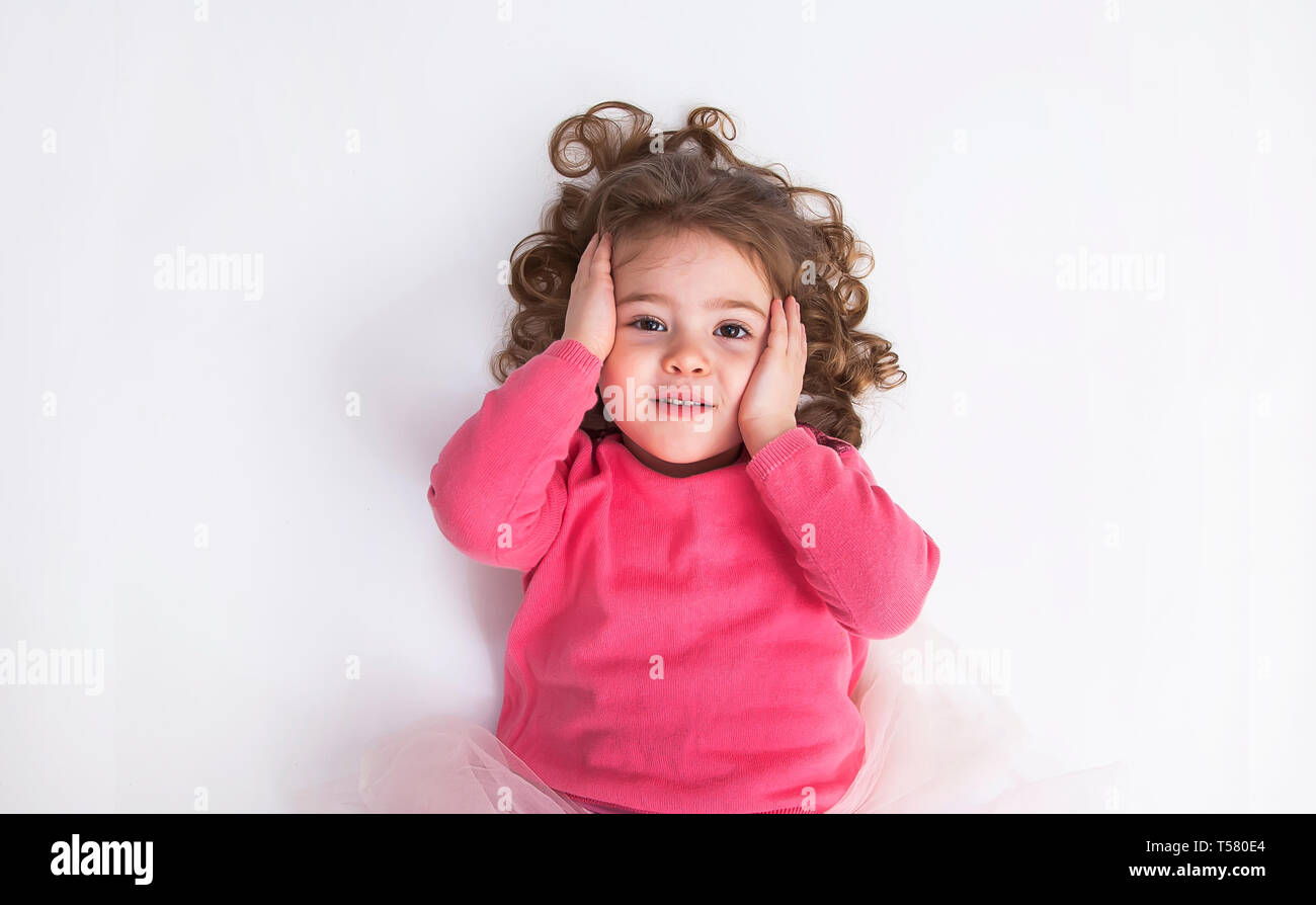 Beautiful little girl lies on the white floor and smile Stock Photo - Alamy