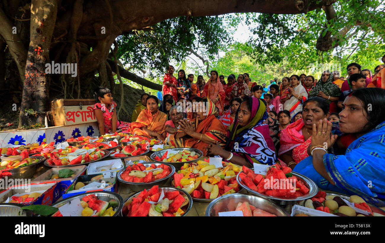 Devotees sit beside arrays of offerings placed under the ancient banyan ...