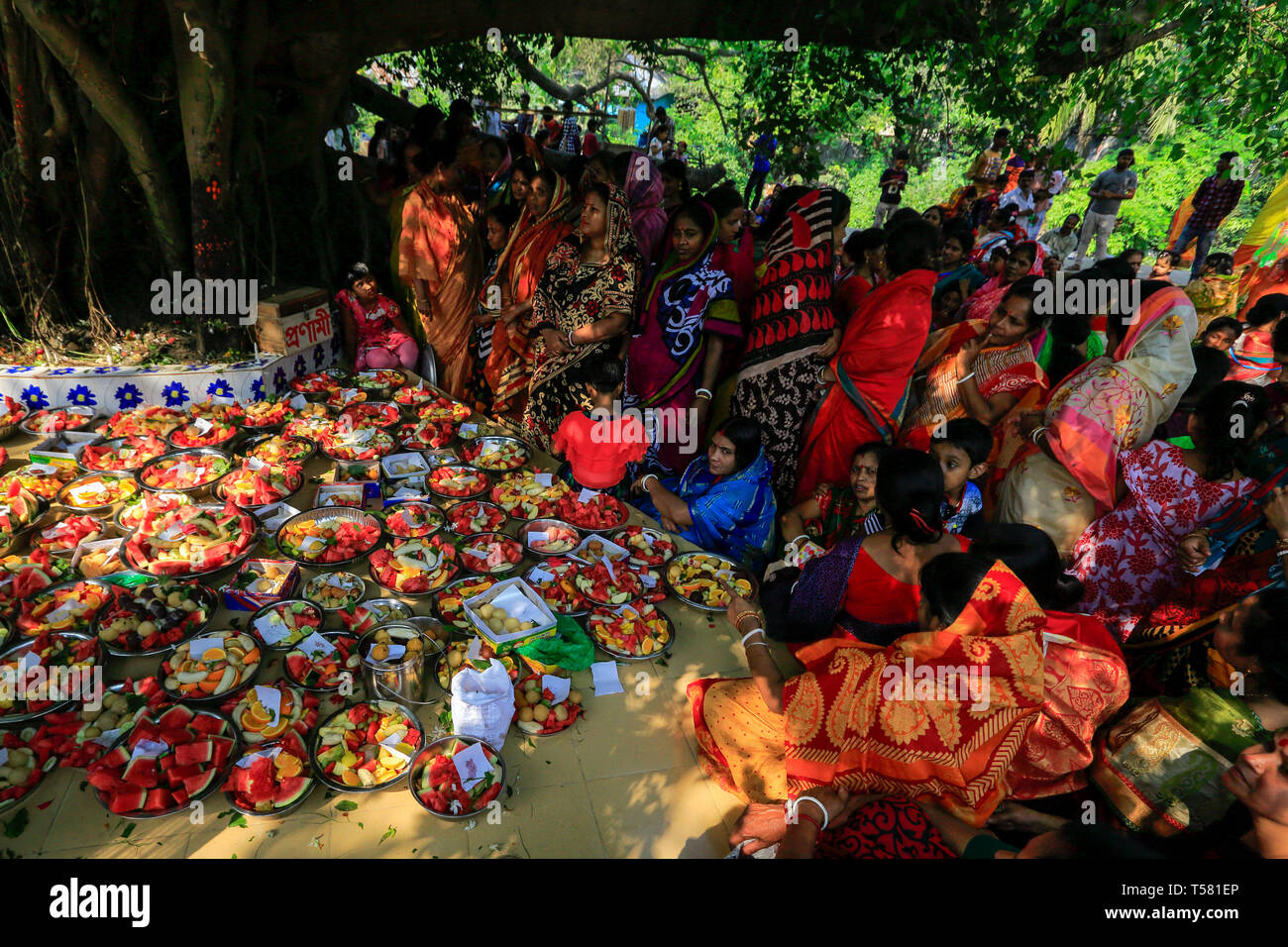 Devotees sit beside arrays of offerings placed under the ancient banyan ...