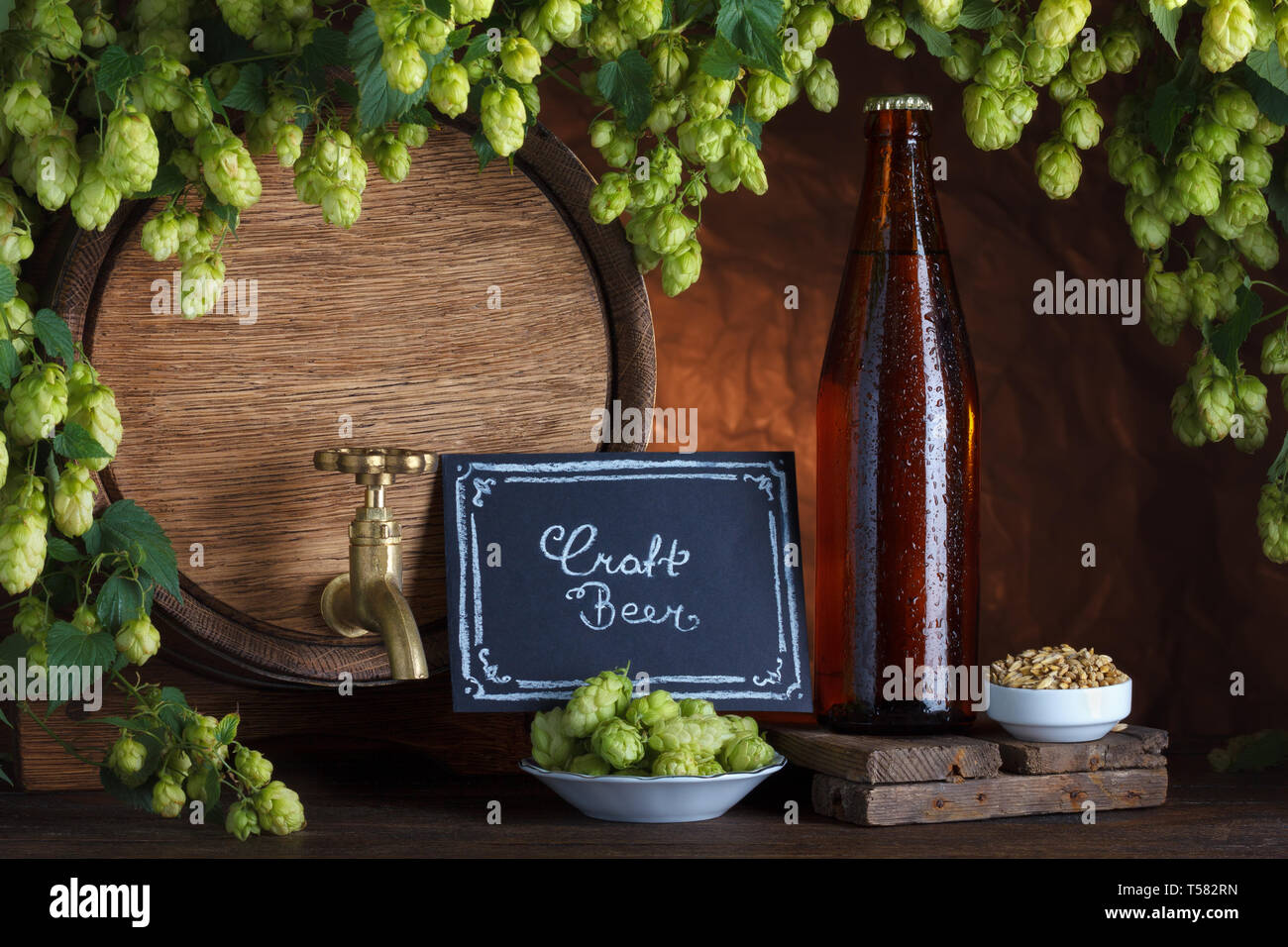 Craft bottled beer with beer barrel and fresh hops with barley for ...