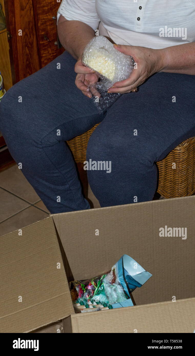 Adult person wrapping household objects in bubble wrap and packing it ...