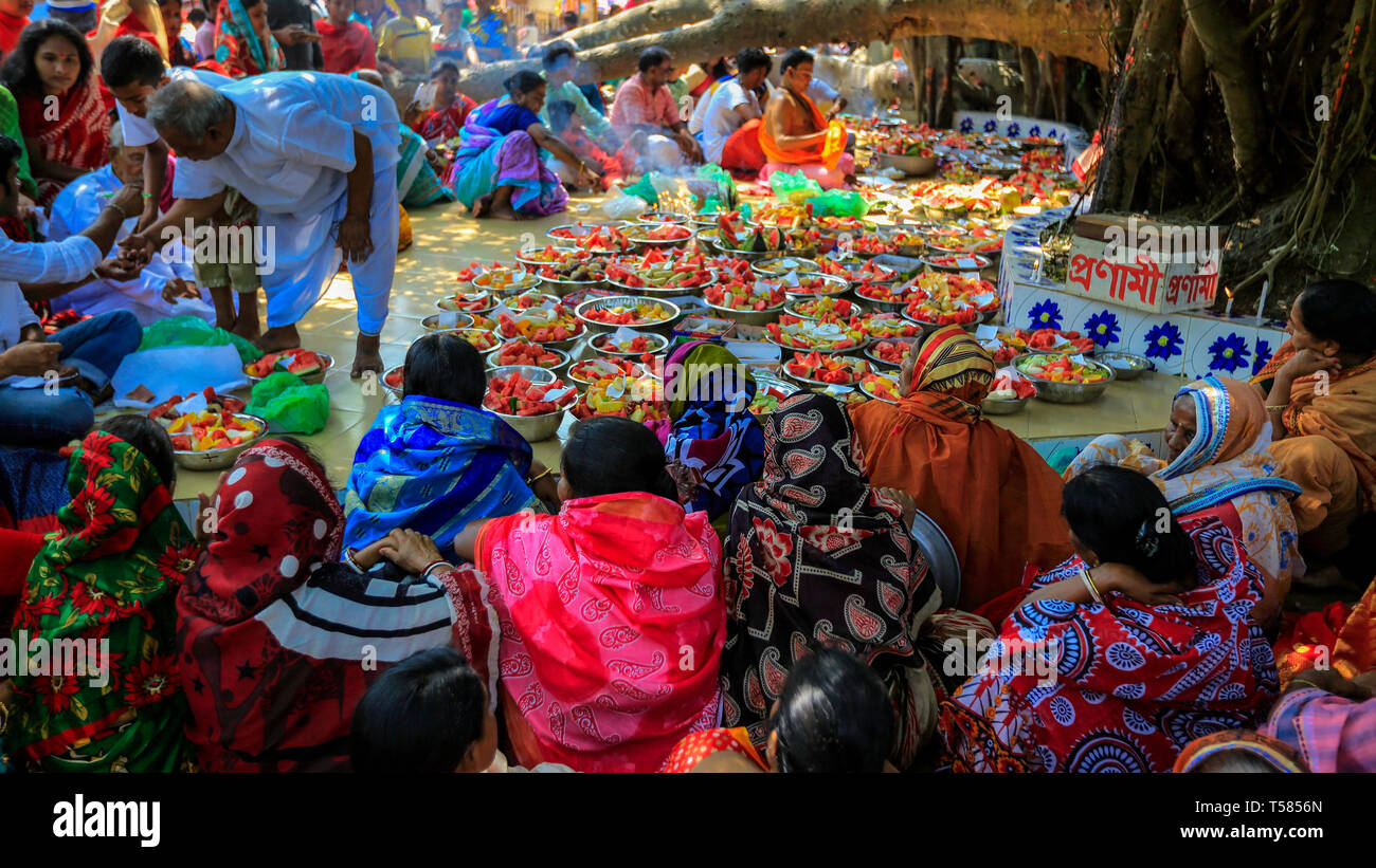 Devotees sit beside arrays of offerings placed under the ancient banyan ...
