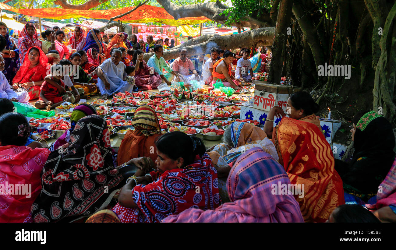 Devotees sit beside arrays of offerings placed under the ancient banyan ...