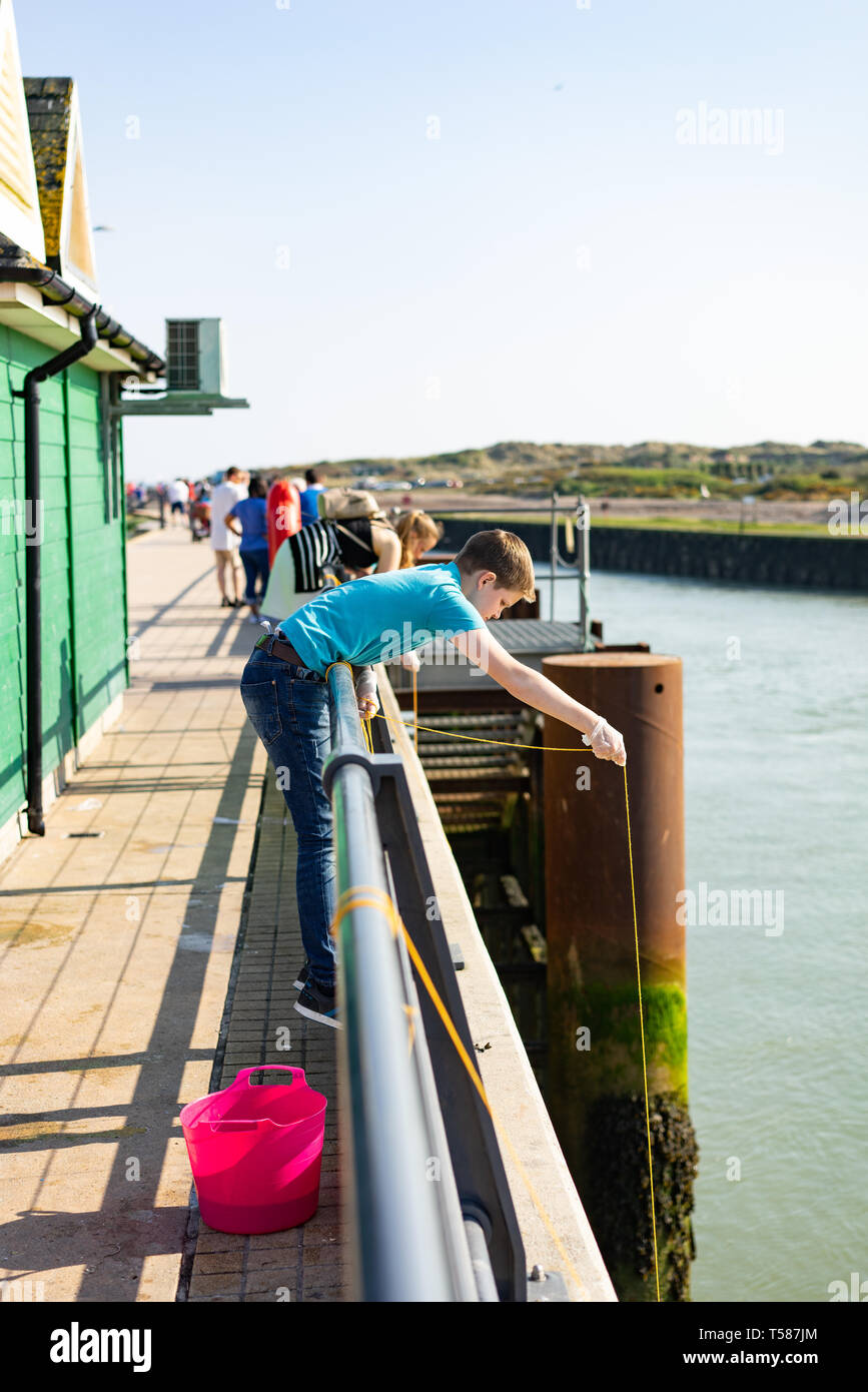 Boy with fishing line crabbing on Littlehampton promenade on a sunny ...