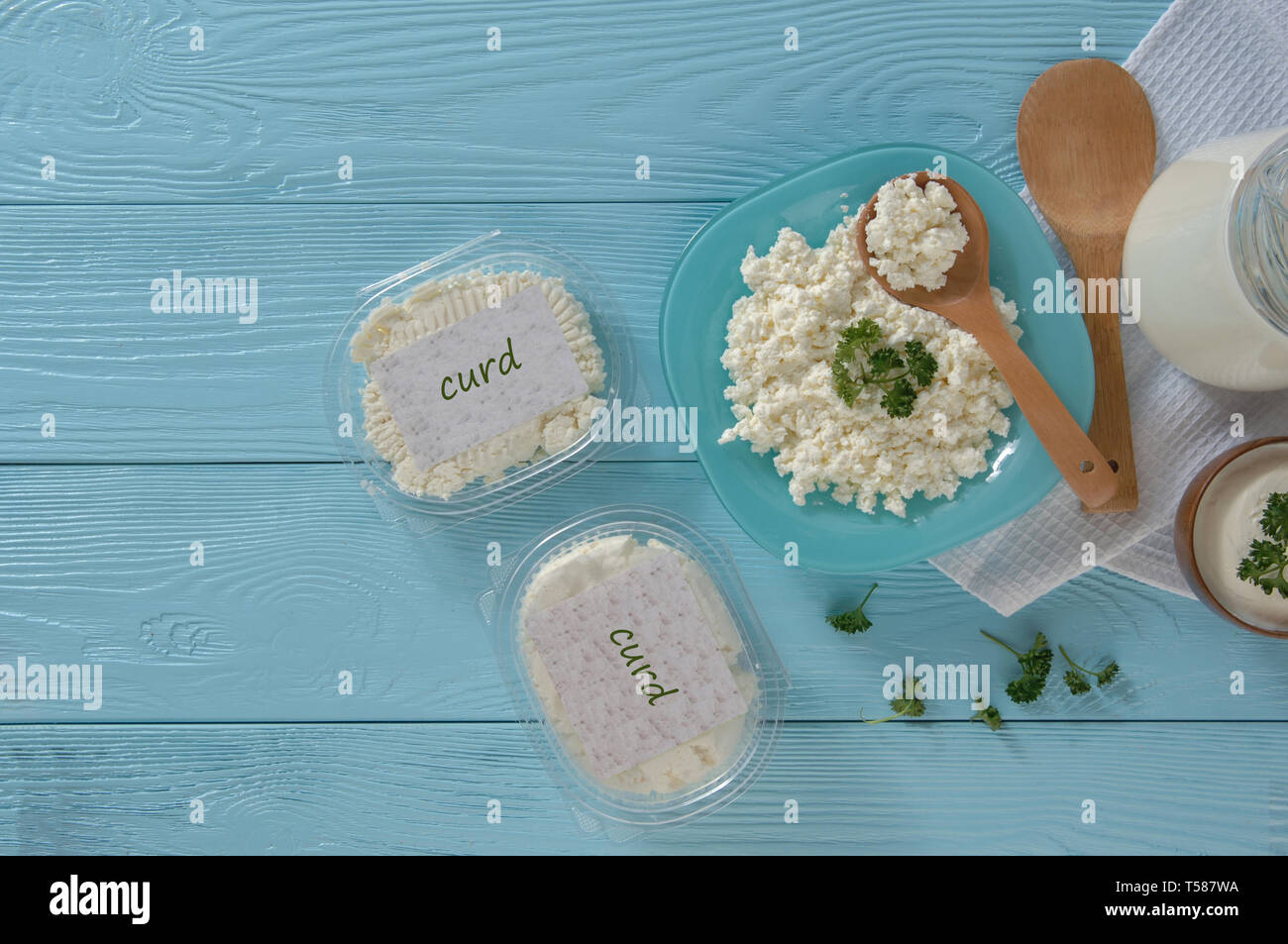 Cottage cheese in plastic packaging and milk on a wooden blue ...