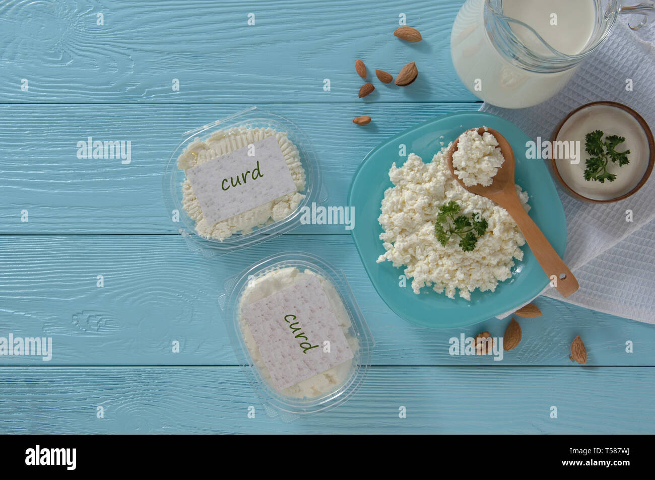 Cottage cheese in plastic packaging and milk on a wooden blue ...