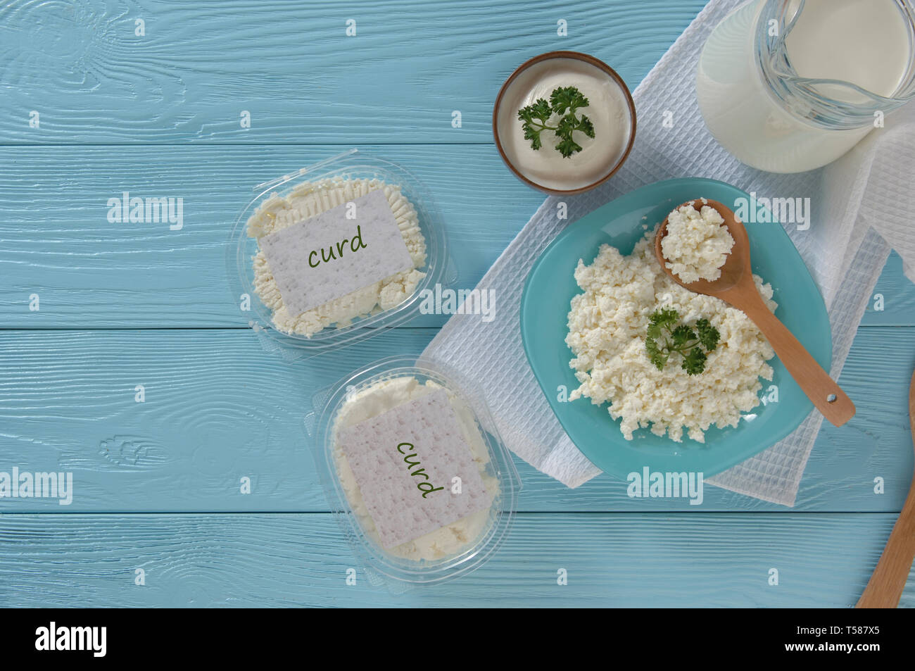 Cottage cheese in plastic packaging and milk on a wooden blue ...