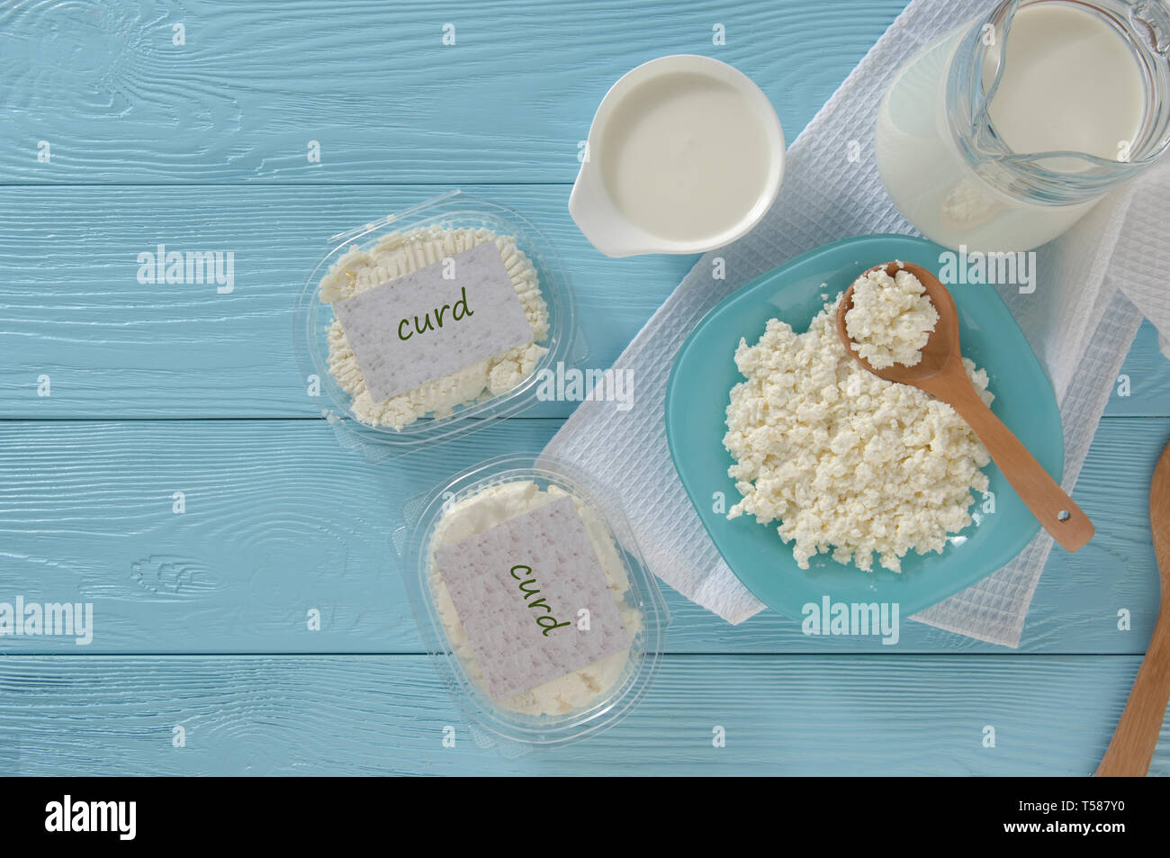 Cottage cheese in plastic packaging and milk on a wooden blue ...