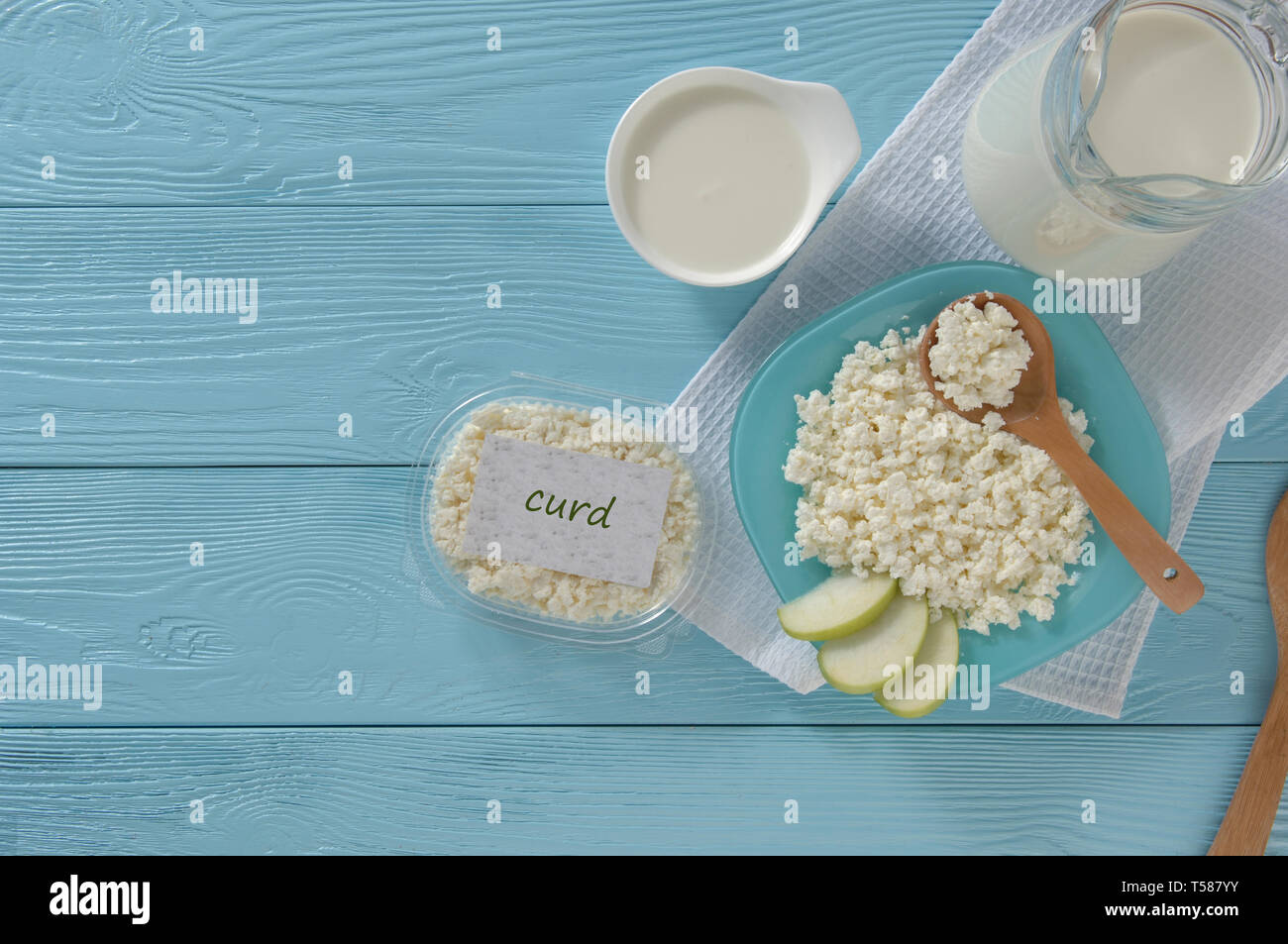 Cottage cheese in plastic packaging and milk on a wooden blue ...
