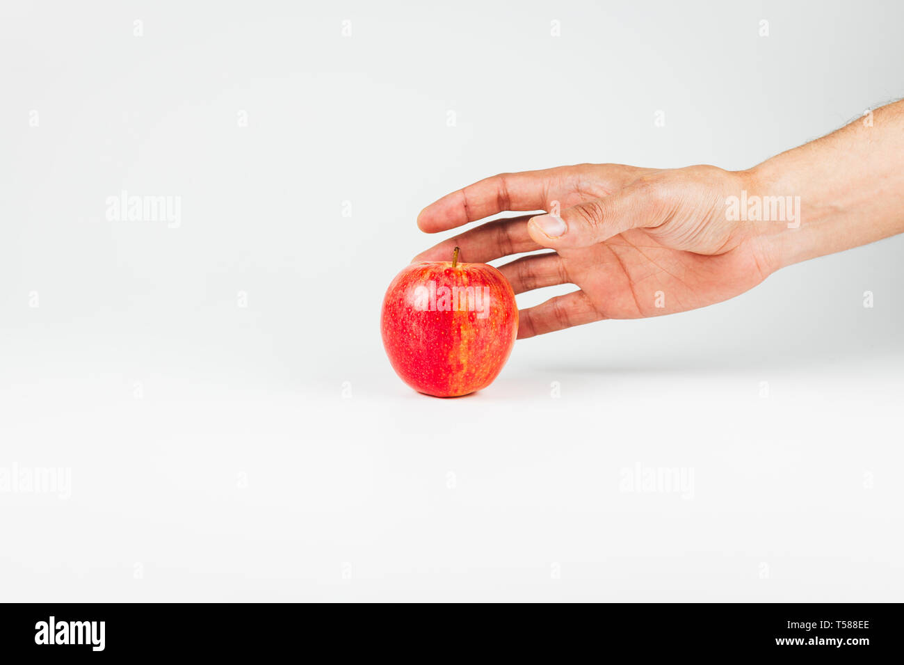 Close-Up Of Hand Reaching Towards Apple Against White Background Stock ...