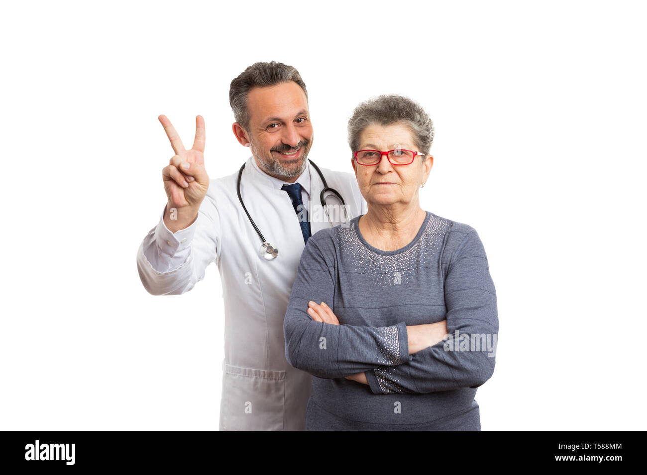 Joking male doctor making peace or victory sign with serous elderly ...