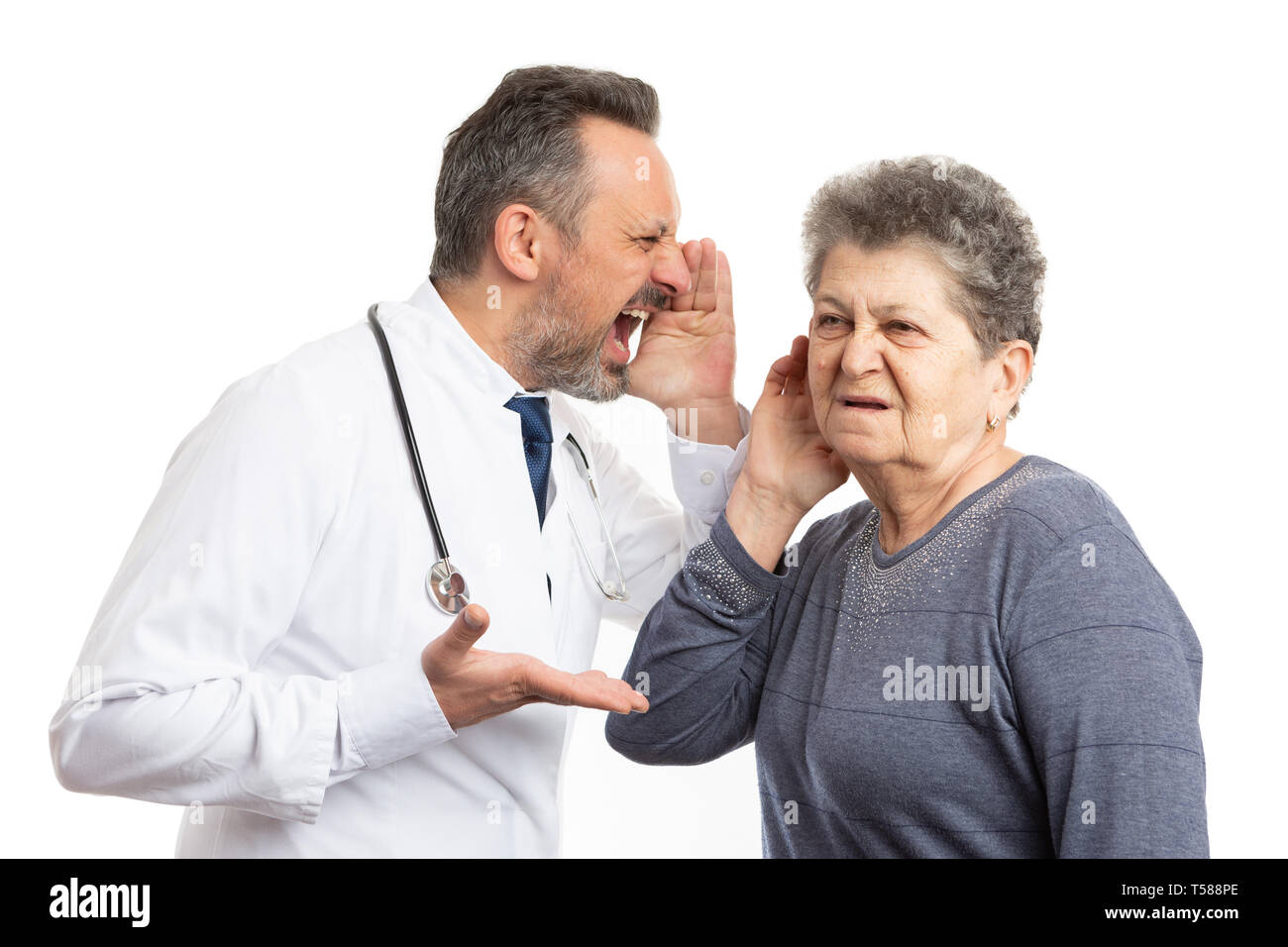 Angry male doctor shouting in elderly deaf patient ear with hand near ...