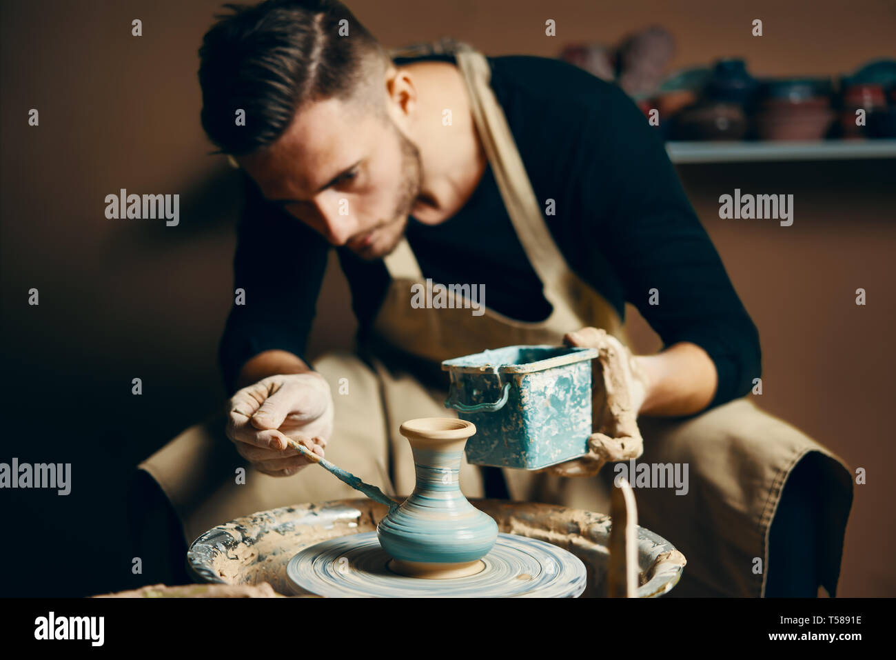 Man painting handmade pottery at ceramic workshop. Art concept Stock ...