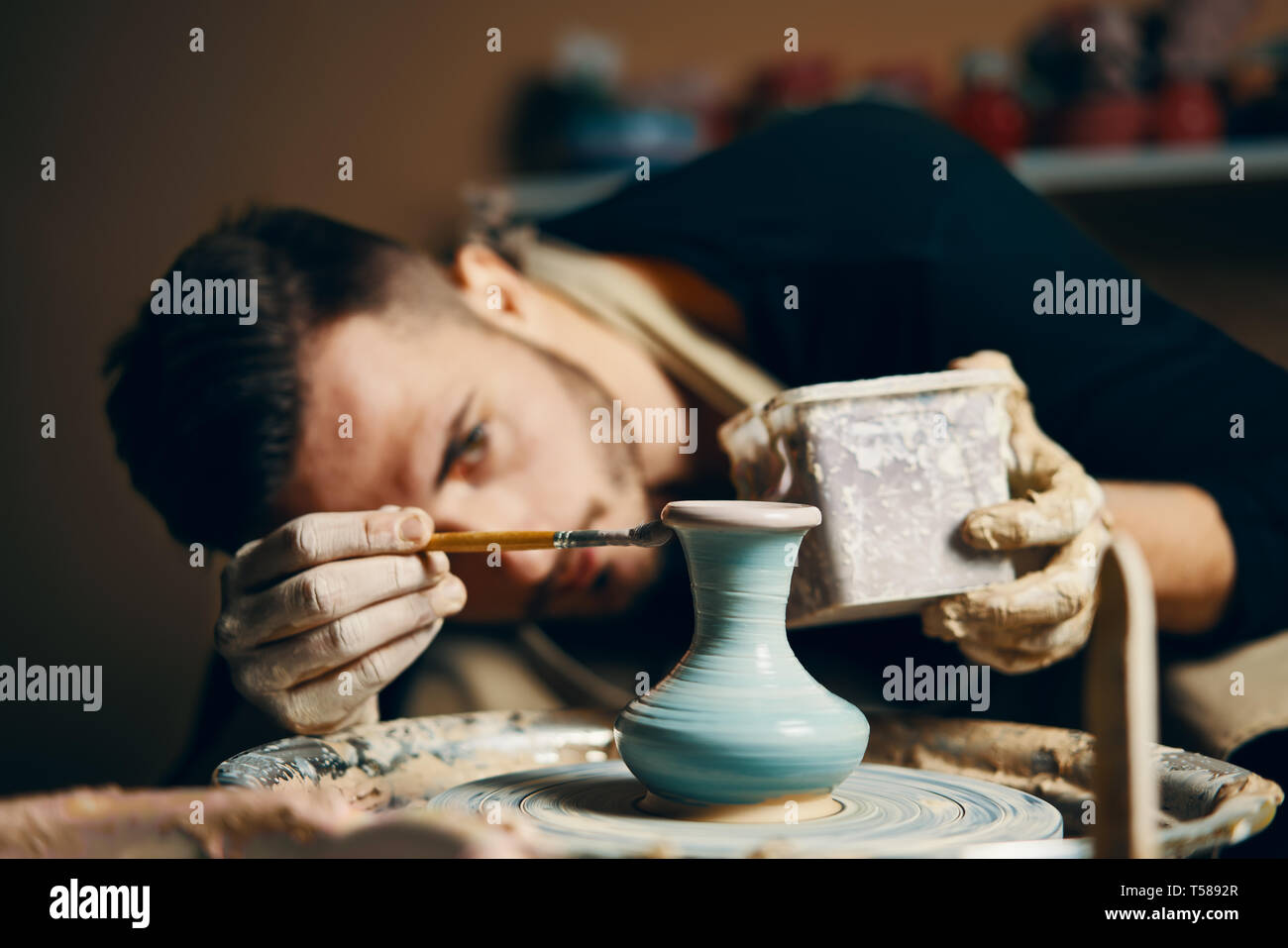 Man painting handmade pottery at ceramic workshop. Art concept Stock ...